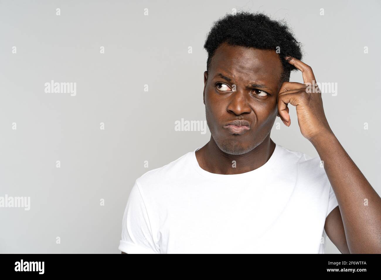 unsure doubtful African man scratching head, looking left doubtfully ...