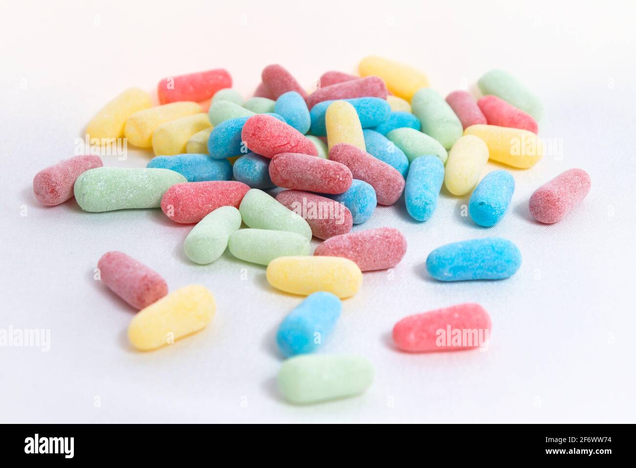 Red, blue, yellow and green sour candies in a pile on a white ...