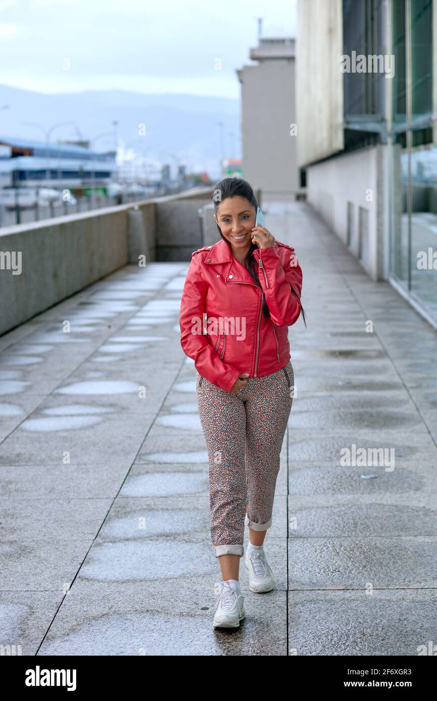 Latina girl in red jacket talking on cell phone in the street Stock ...