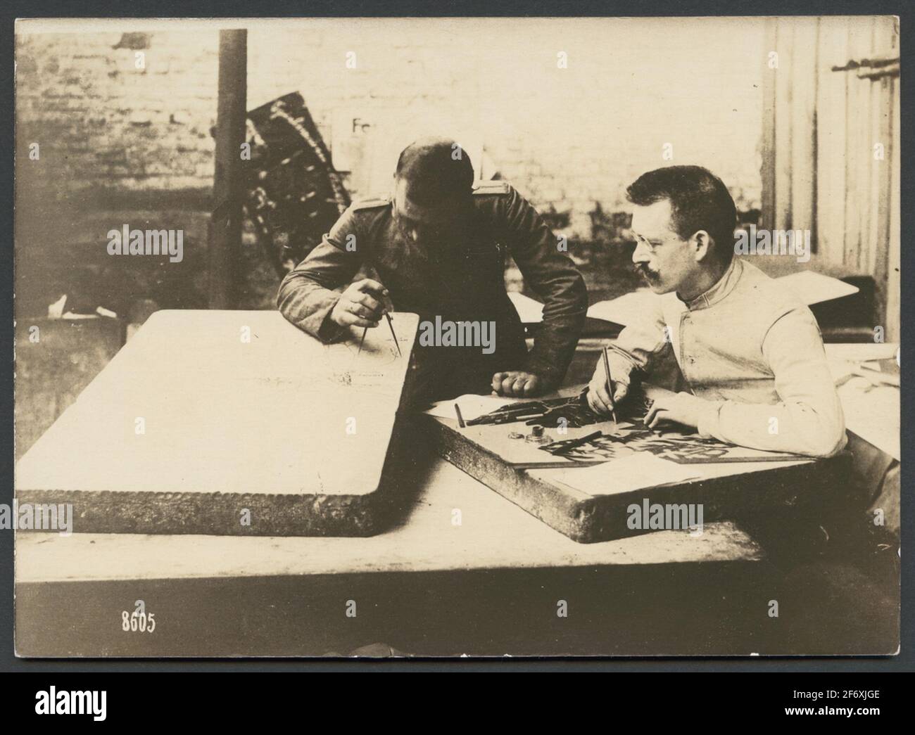 The picture shows two cartographers that are drawing maps on thick ...