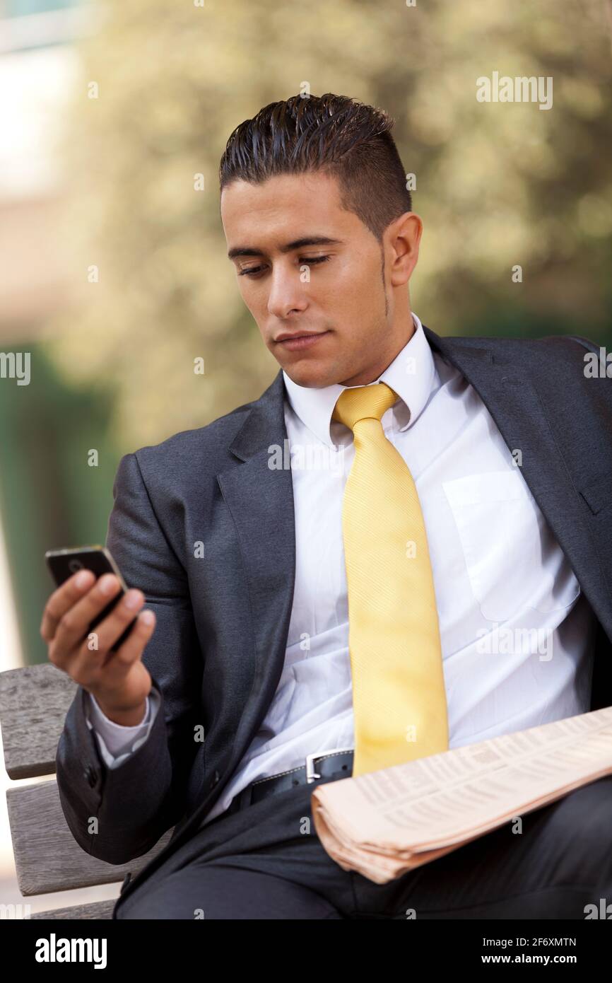 Businessman sited in a bench, sending short messages over his cellphone ...