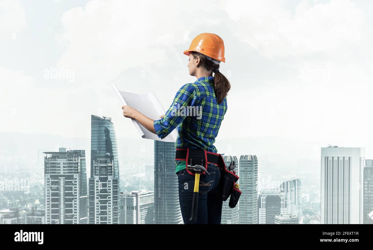 Female engineer in hardhat standing with blueprint Stock Photo - Alamy