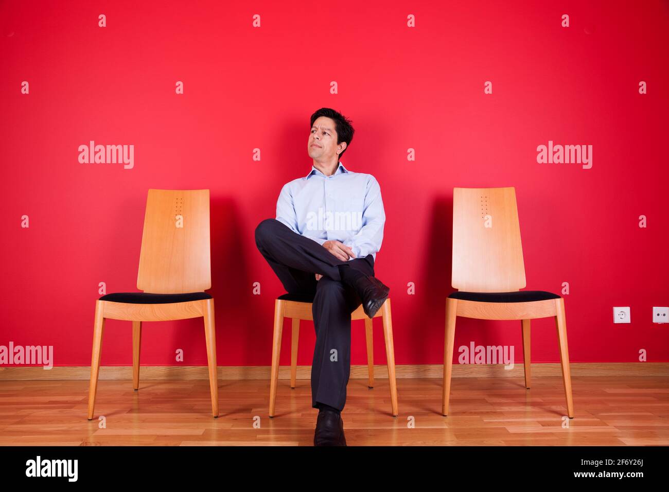 Businessman sited next to a red wall Stock Photo - Alamy