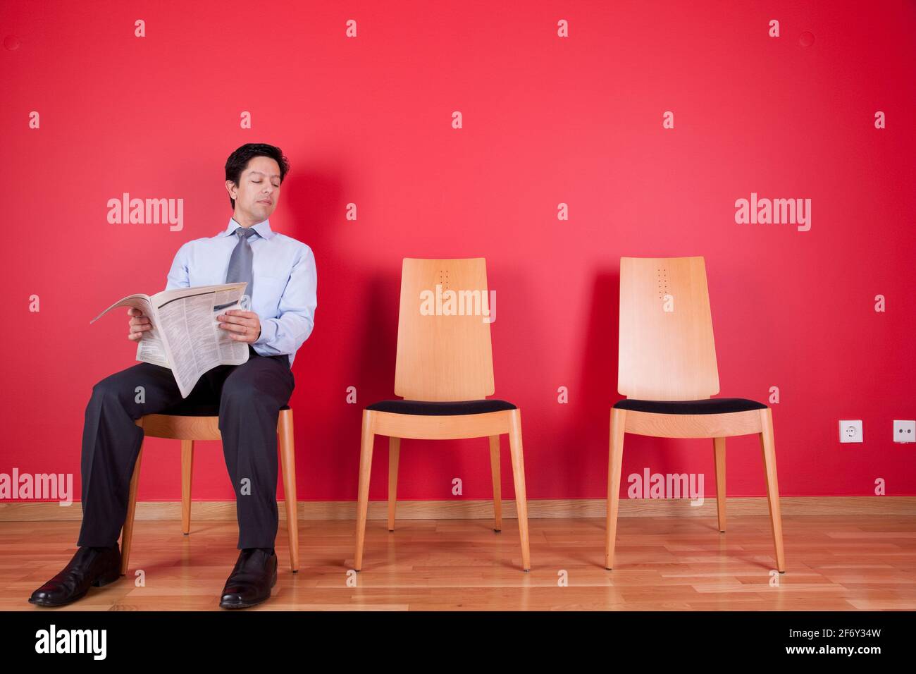 businessman reading the newspaper siting on a chair Stock Photo - Alamy