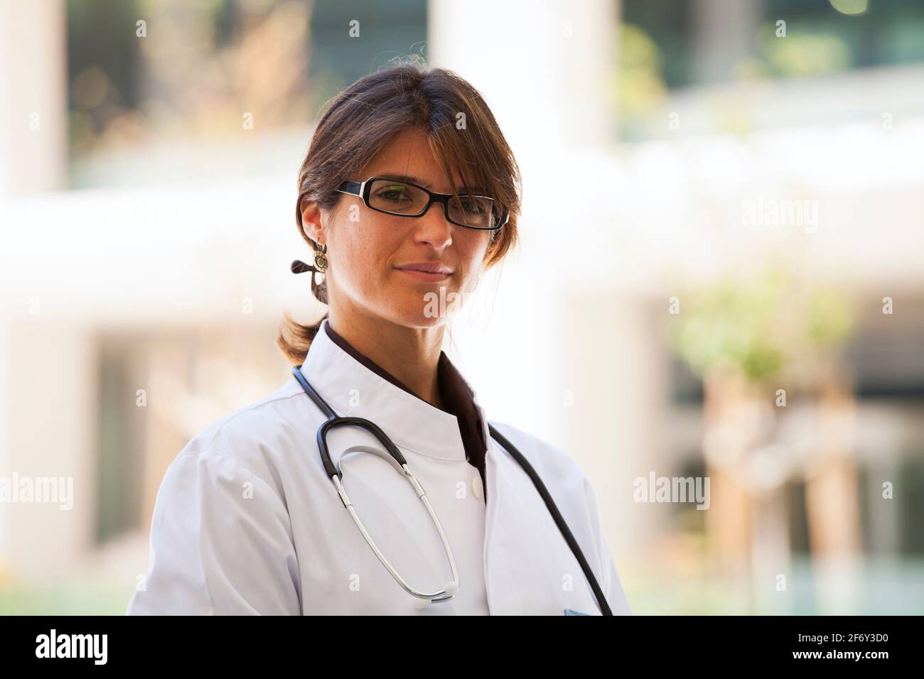 Friendly female doctor smiling to you nest to a clinic Stock Photo - Alamy