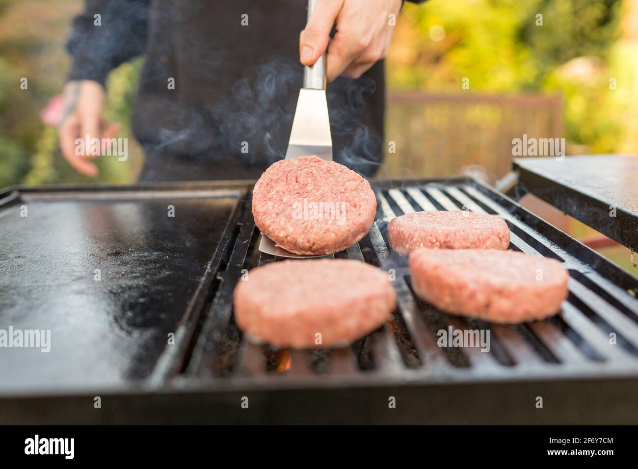 A happy young man cooking meat burgers on barbecue grill - leisure ...