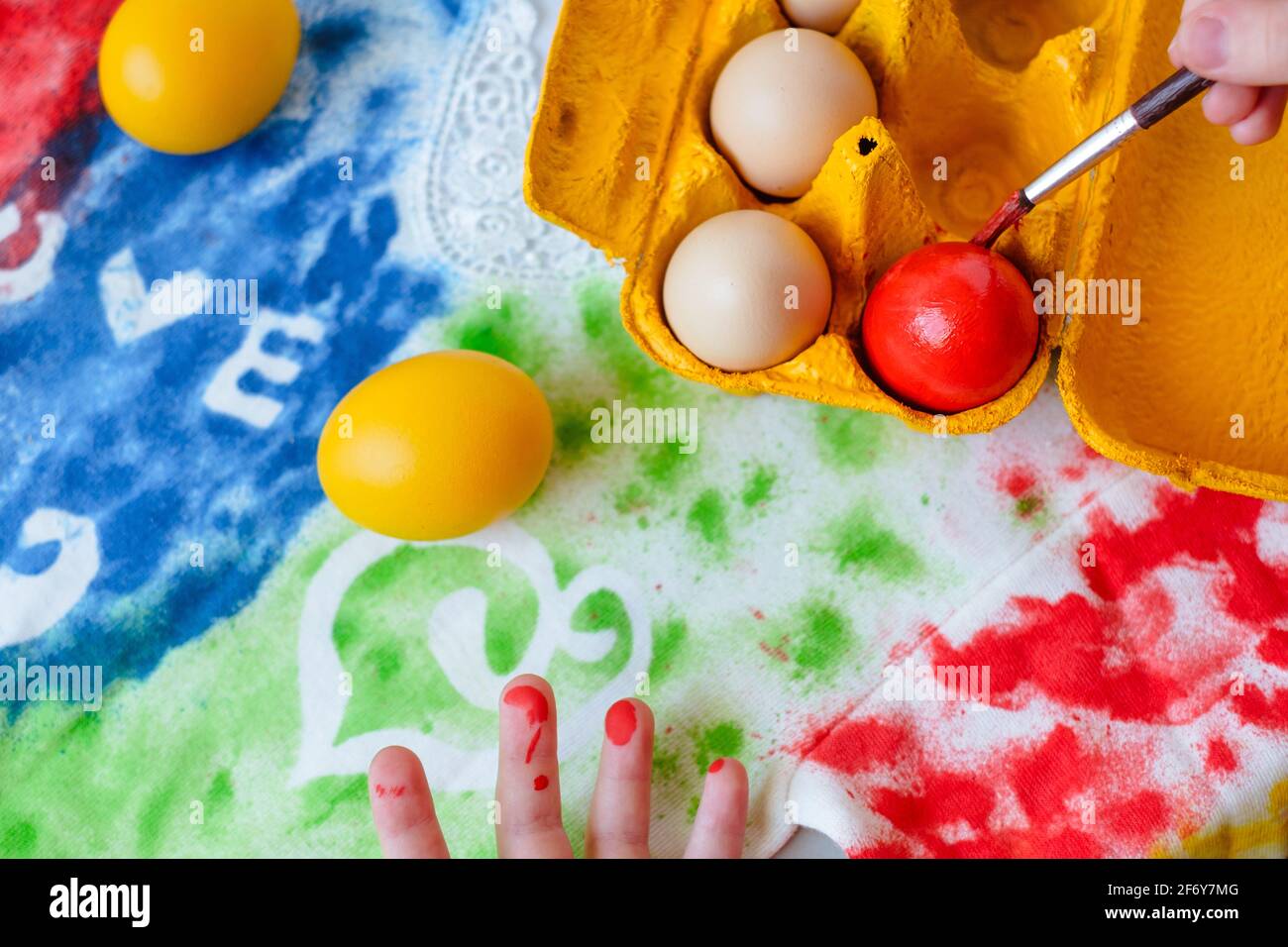 children's hands draw an easter egg paint brush in red. paint stains on ...