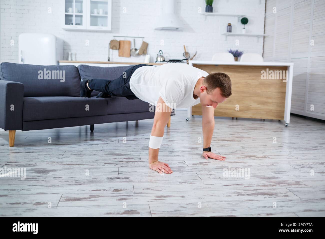 A young man goes in for sports at home, he does push-ups on the couch ...
