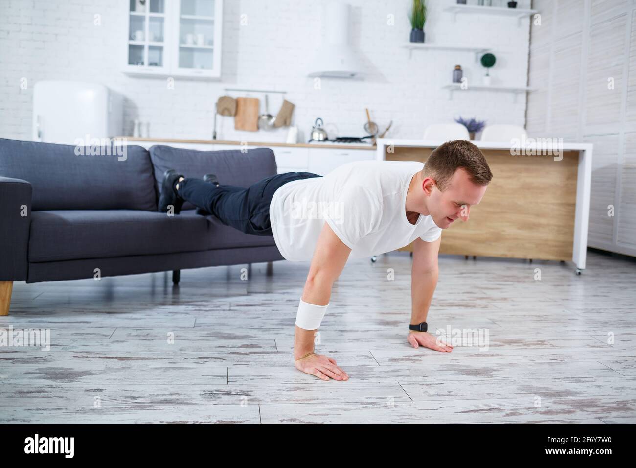 A young man goes in for sports at home, he does push-ups on the couch ...