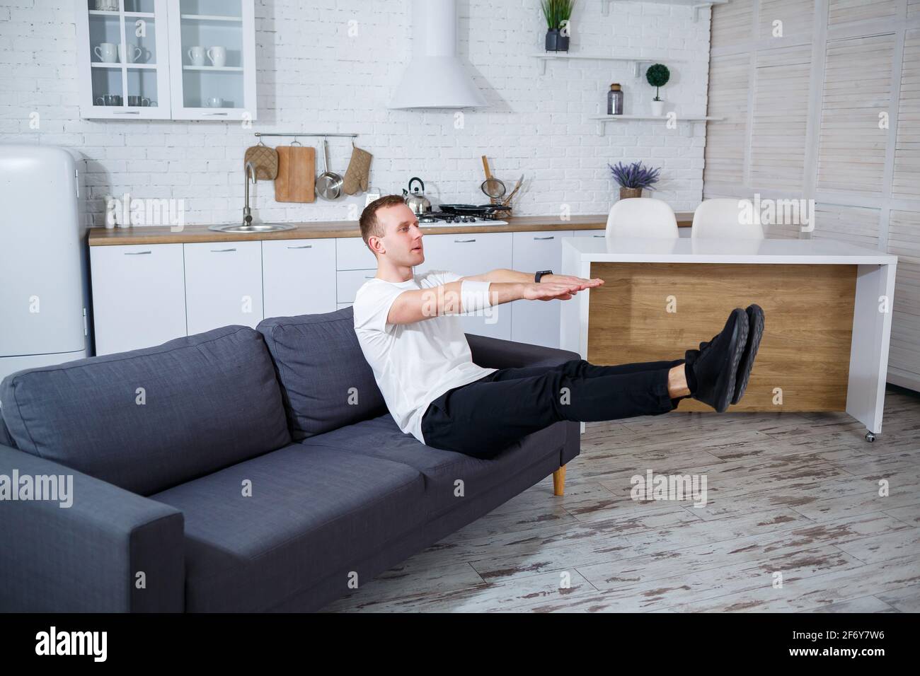 A young man goes in for sports at home, he does push-ups on the couch ...