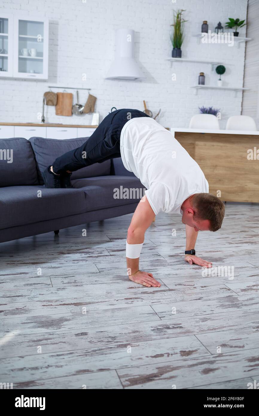 A young man goes in for sports at home, he does push-ups on the couch ...