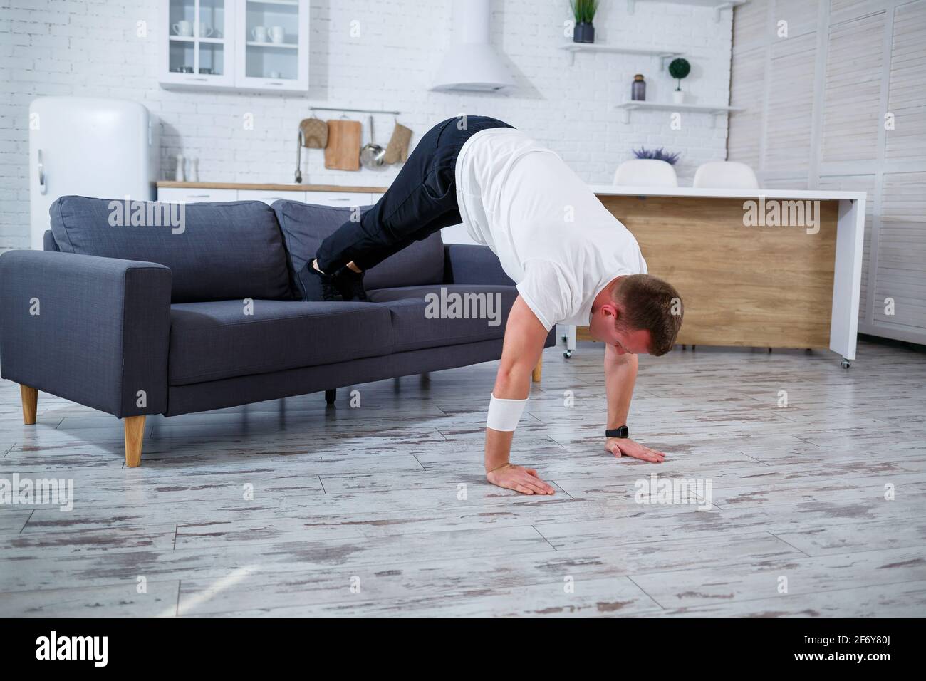 A young man goes in for sports at home, he does push-ups on the couch ...