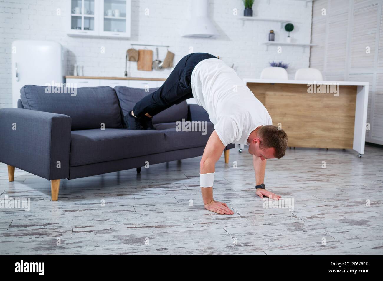 A young man goes in for sports at home, he does push-ups on the couch ...