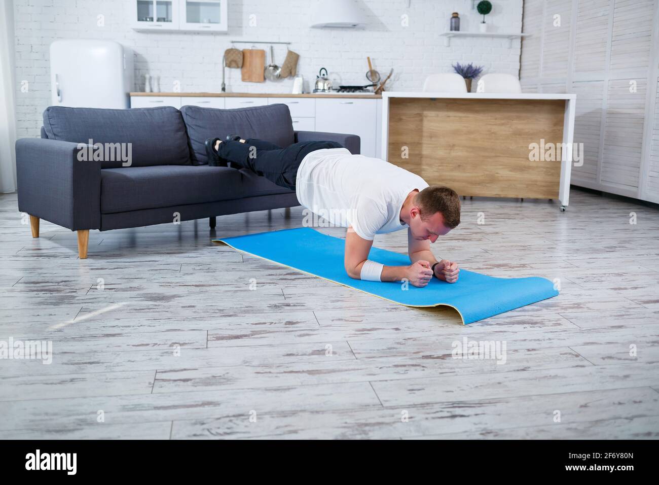 A young man goes in for sports at home, he does push-ups on the couch ...