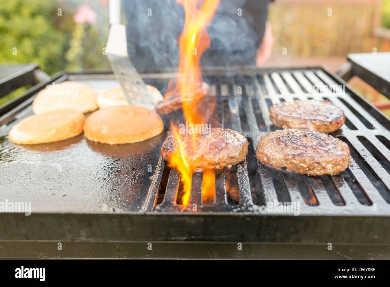 A happy young man cooking meat burgers on barbecue grill - leisure ...