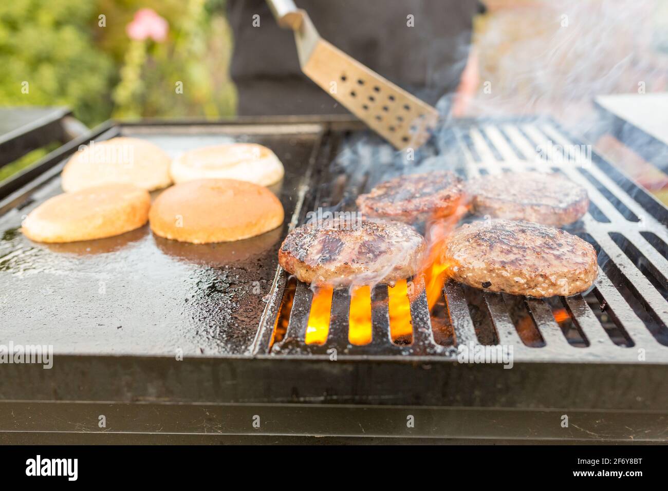 A happy young man cooking meat burgers on barbecue grill - leisure ...