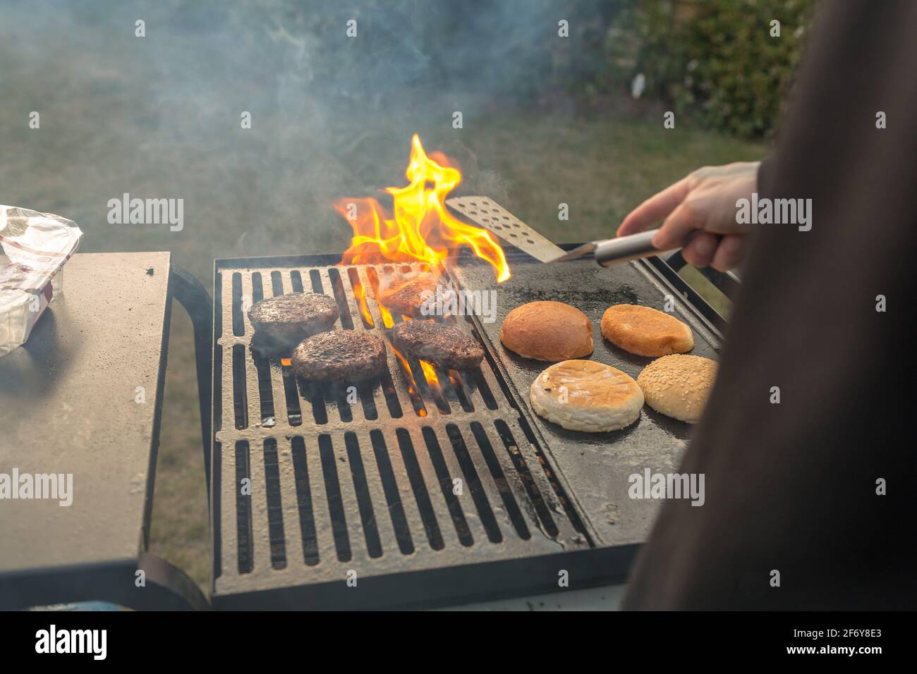 A happy young man cooking meat burgers on barbecue grill - leisure ...