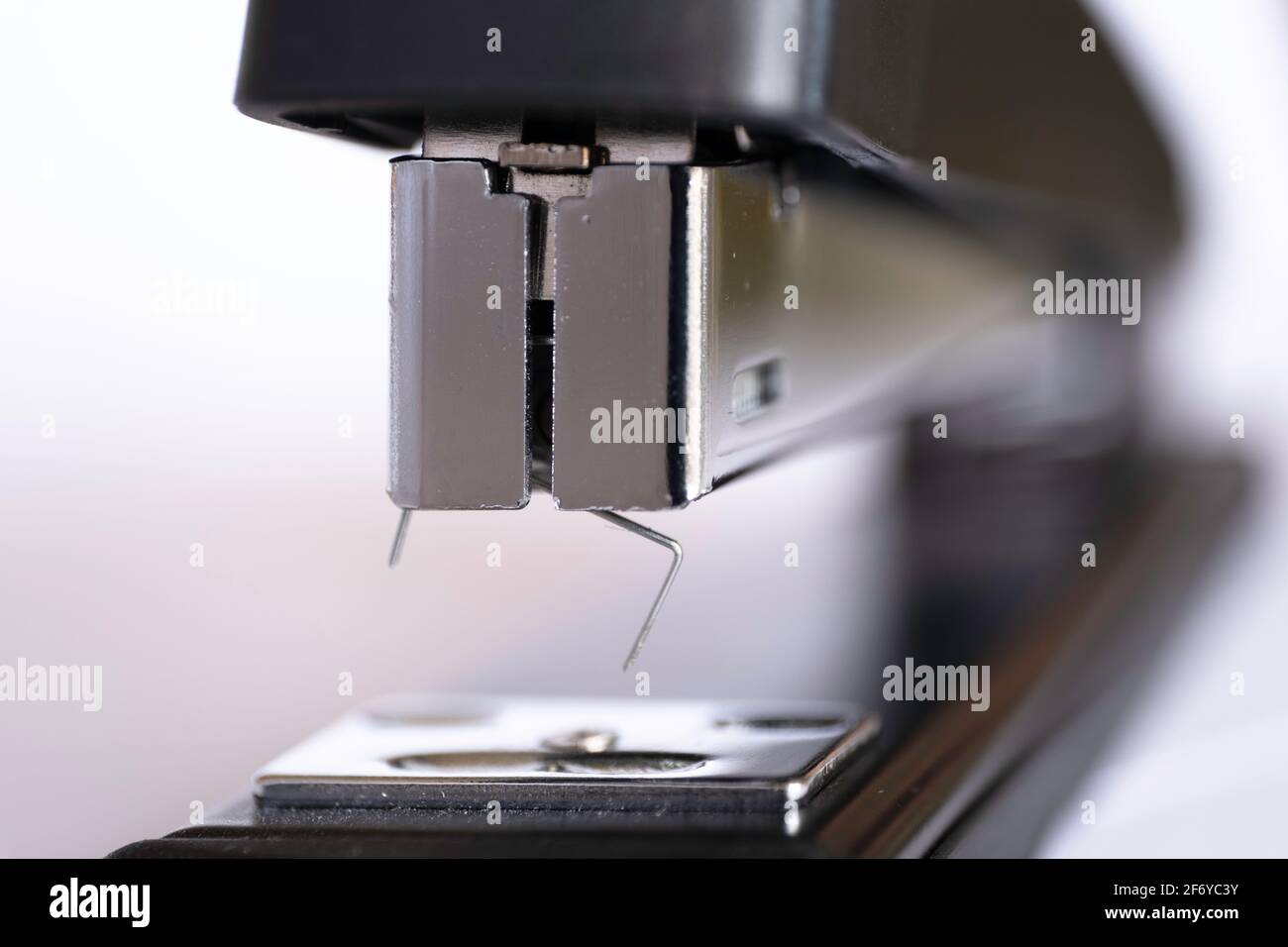 Close-up front view of a black stapler with a staple being pushed out ...