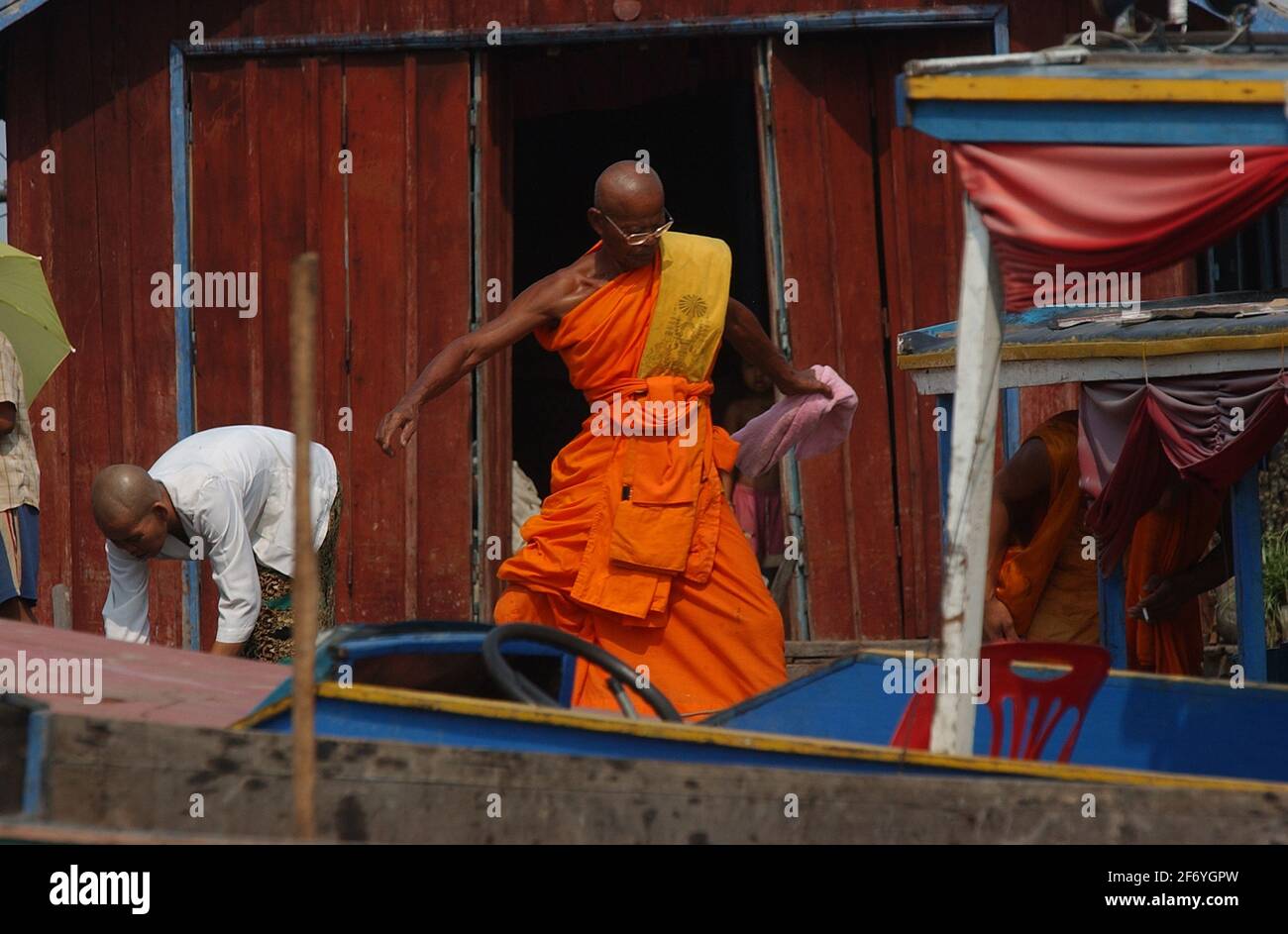 CAMBODIA 2005 A BUDDHIST MONK BOARDS HIS BOAT AT THE FLOATING VILLAGE ...
