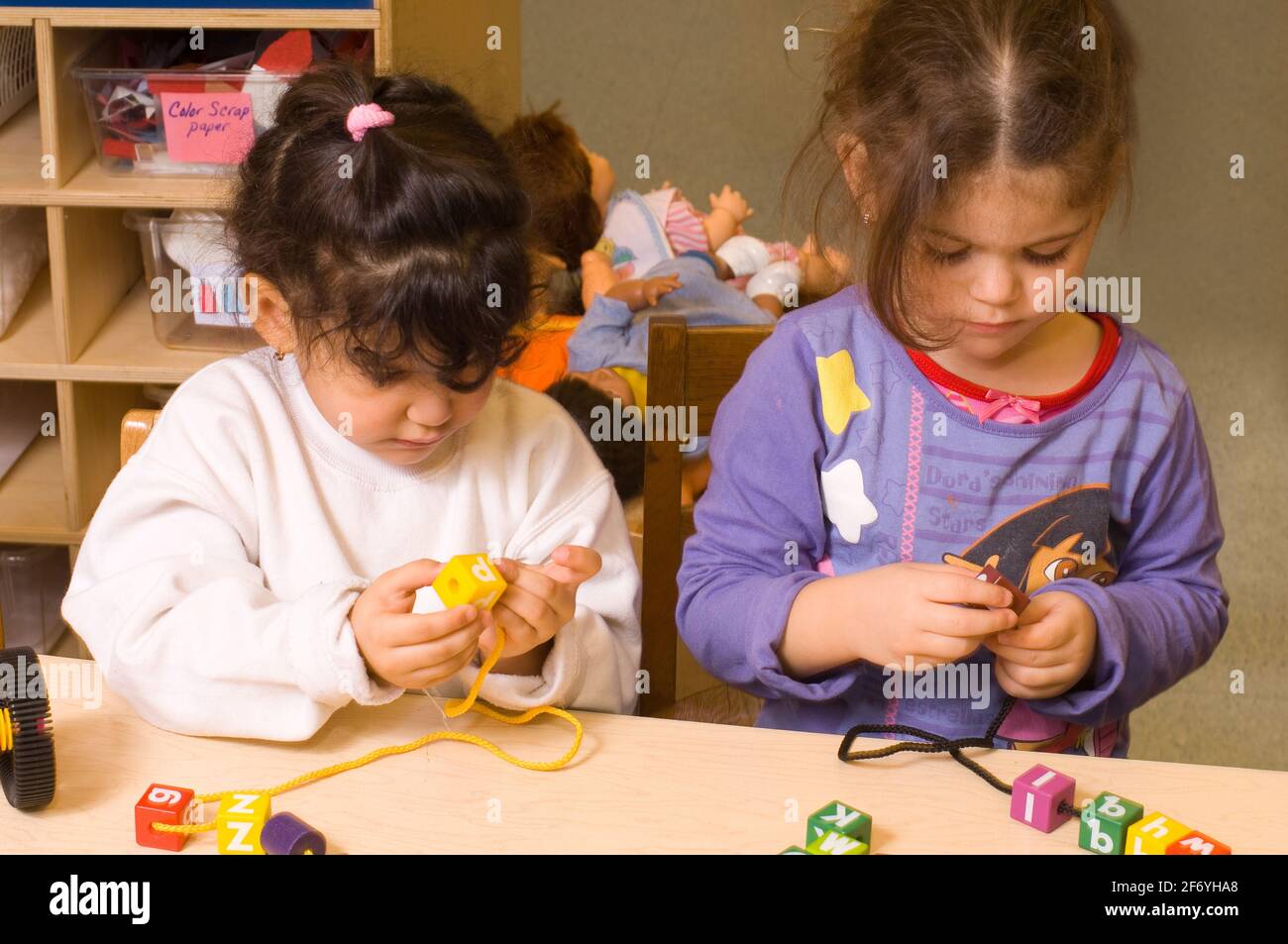 Education preschool 3-4 year olds two girls sitting side by side both ...