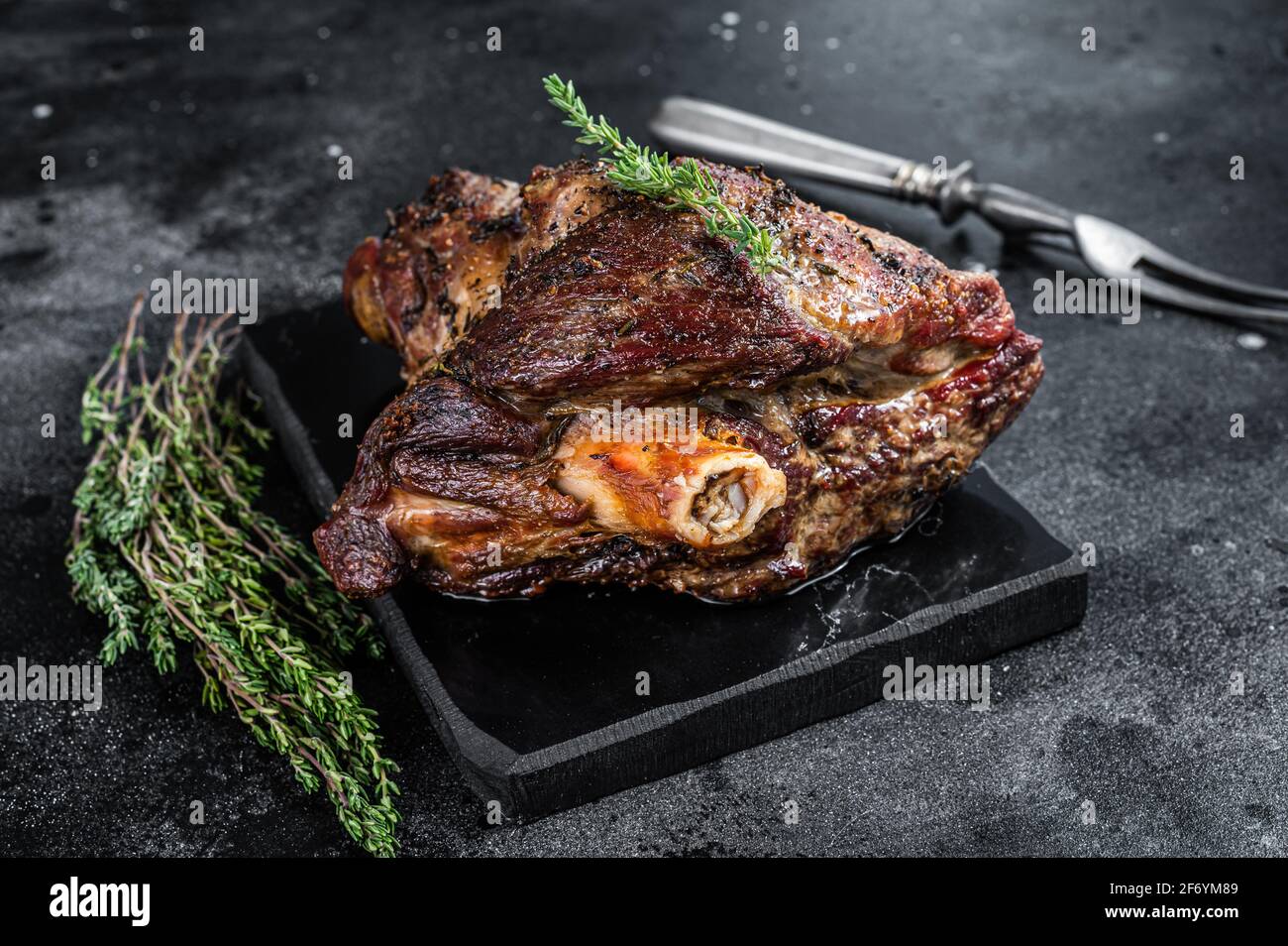 Oven Roasted lamb mutton whole leg with thyme. Black background. Top ...