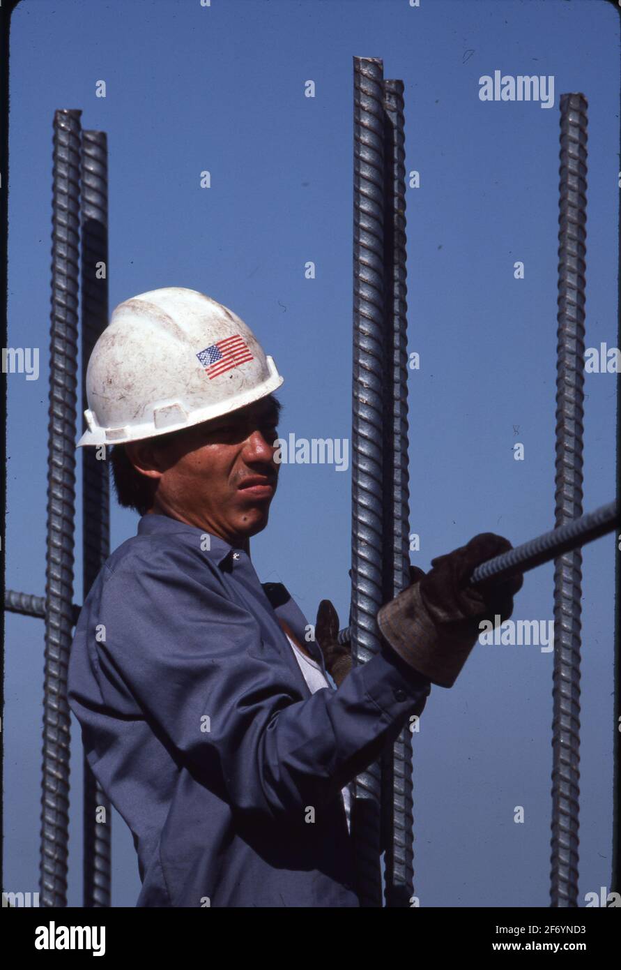 Hispanic construction worker wears a hard hat for safety at a high-rise ...