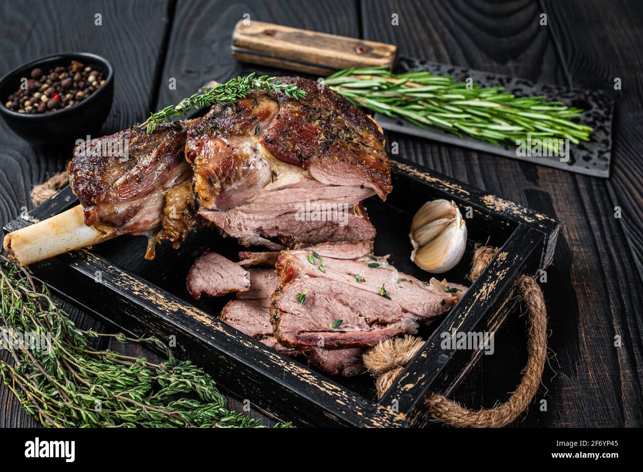 Roasted mutton lamb leg sliced in a wooden tray with meat cleaver ...