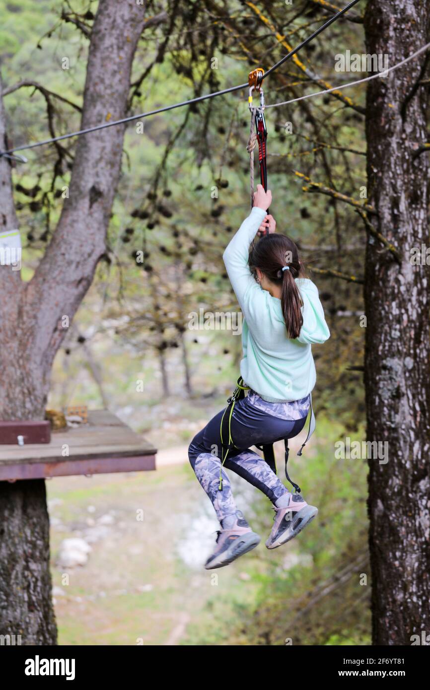 young girl in sportswear jumping from tree to tree, canopy facility ...