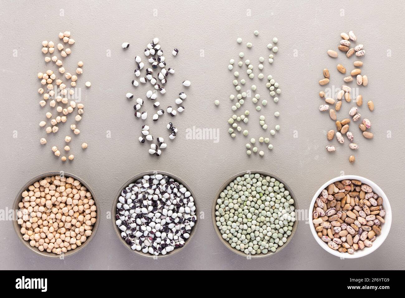 Different types of legumes in bowls and scattered in the background ...