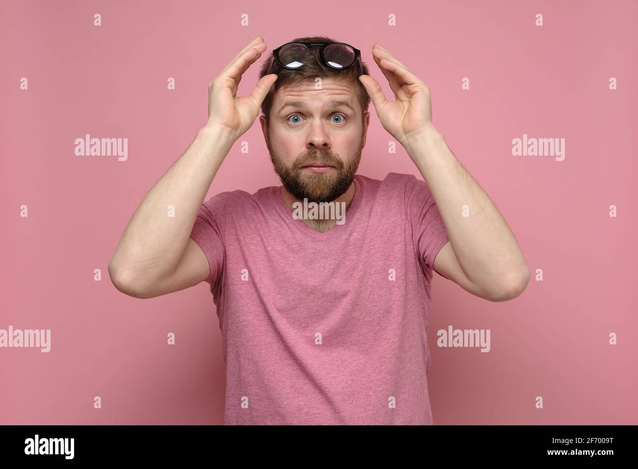 Surprised, attractive bearded man raised glasses and looked ...