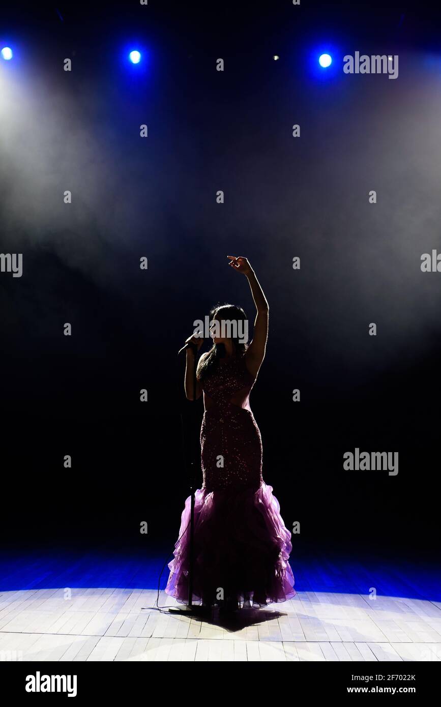 Female singer on the stage holding a microphone Stock Photo - Alamy