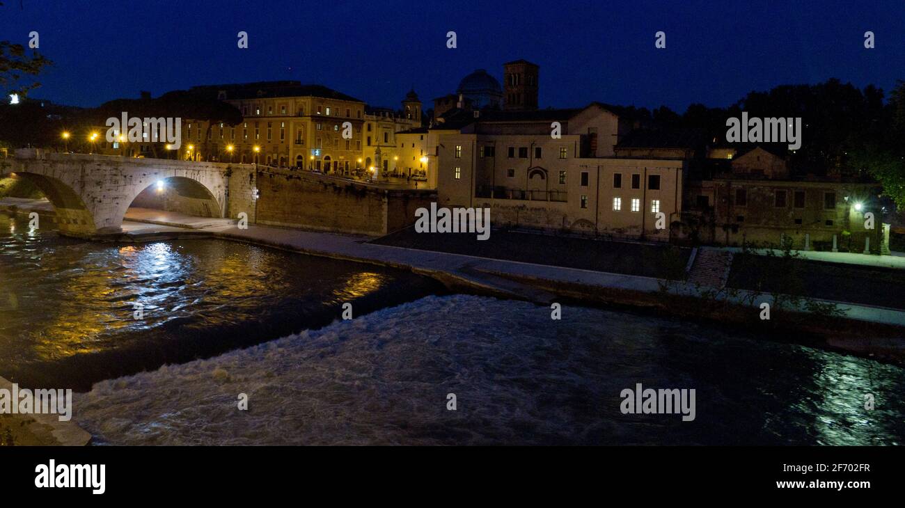 A view of the Tiberine Island at night with Tiber river flowing in the ...