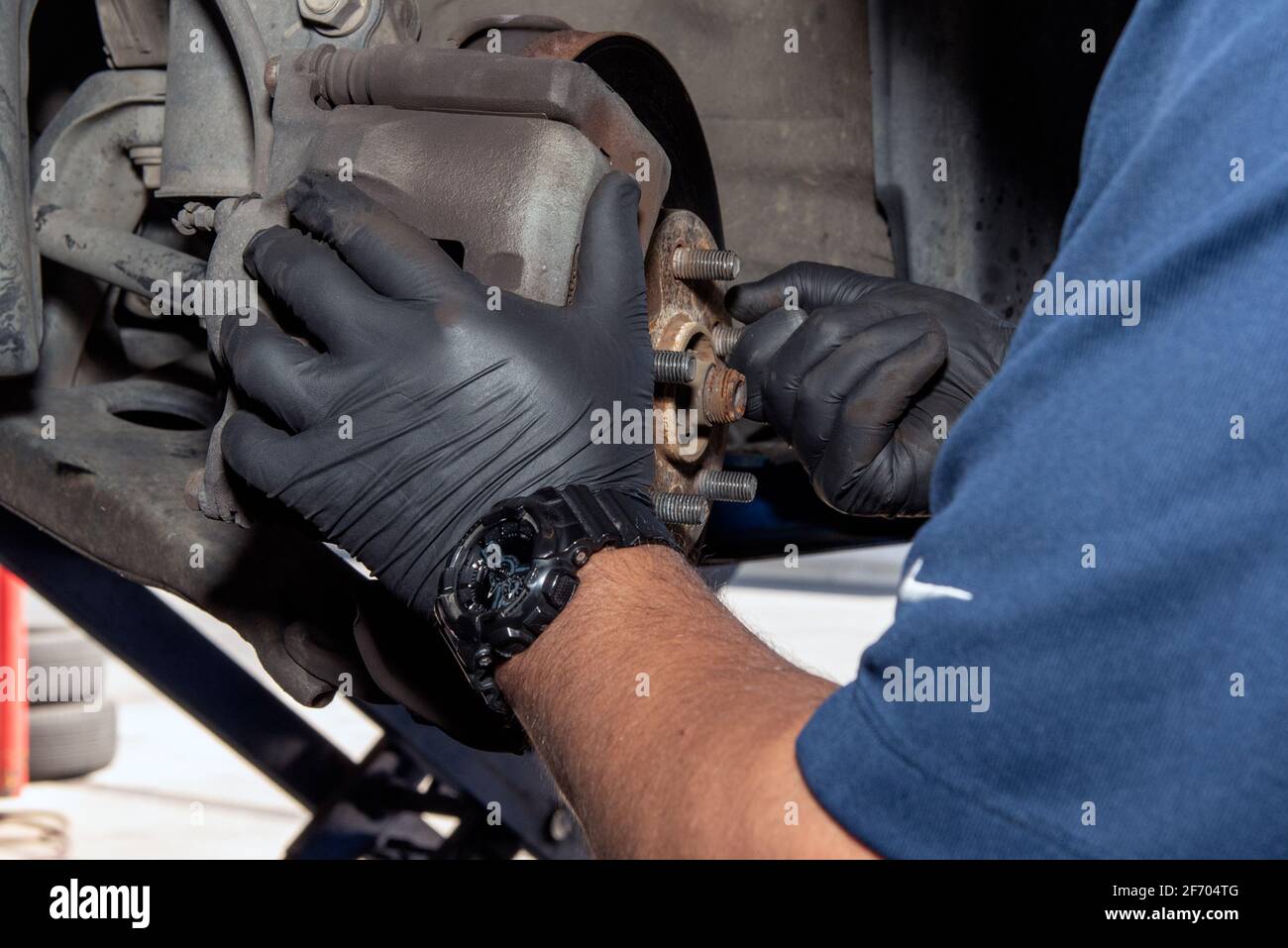 Gloved hands of the mechanic grasps a threaded lug on the vehicle wheel ...