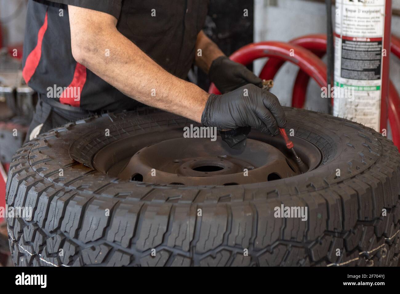 Mechanics gloved hand adjusts the inflated tire pressure of vehicle ...