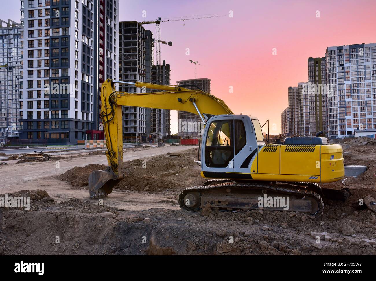Excavator during earthmoving work at construction site on sunset ...