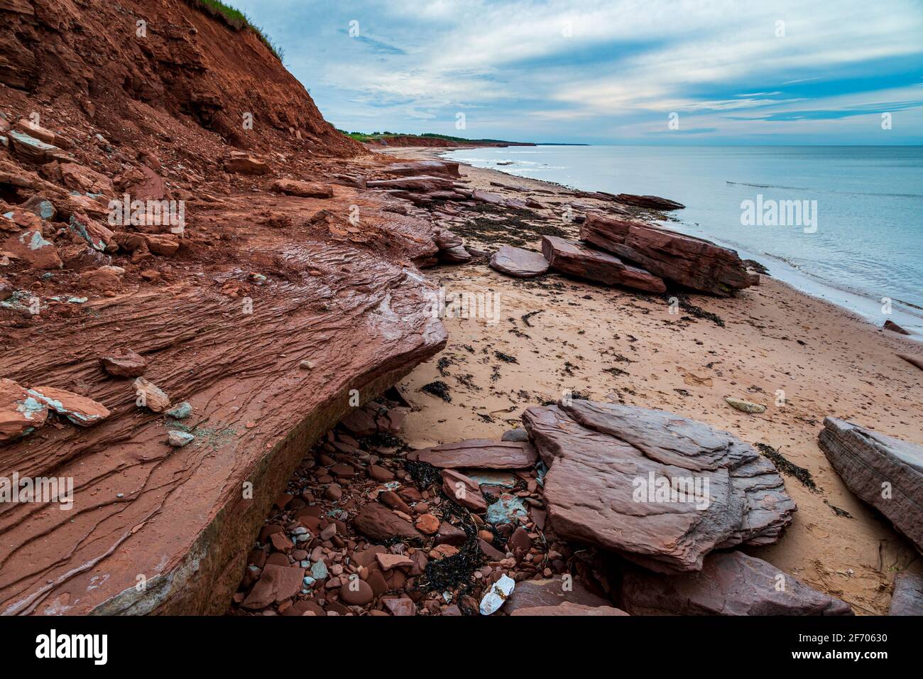 Red and Turquoise sandstone cliff and rocks at Cavendish beach of ...