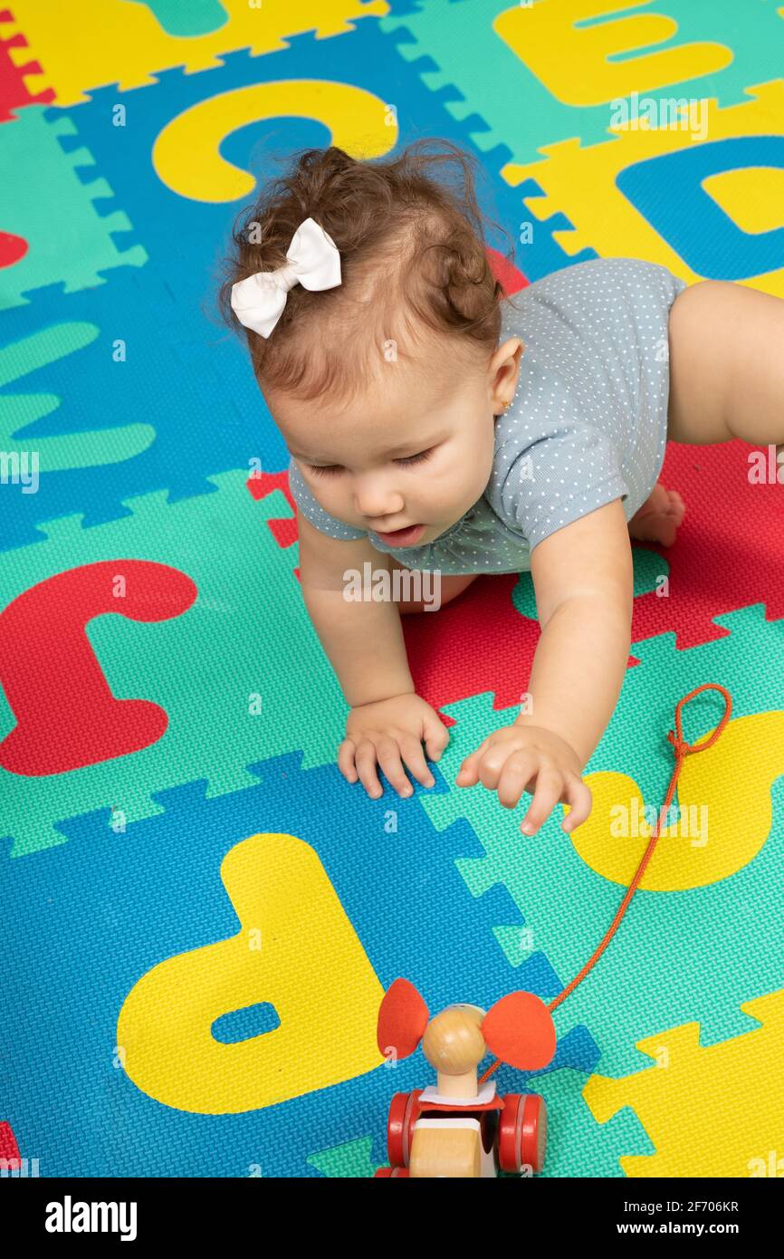 7 month old baby girl crawling toward toy, reaching for toy Stock Photo ...