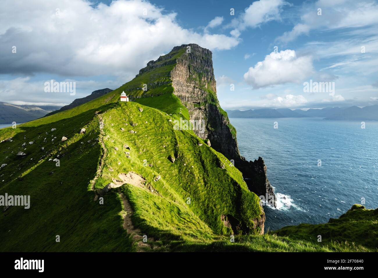 Green faroese hills and Kallur lighthouse on mountains of Kalsoy island ...