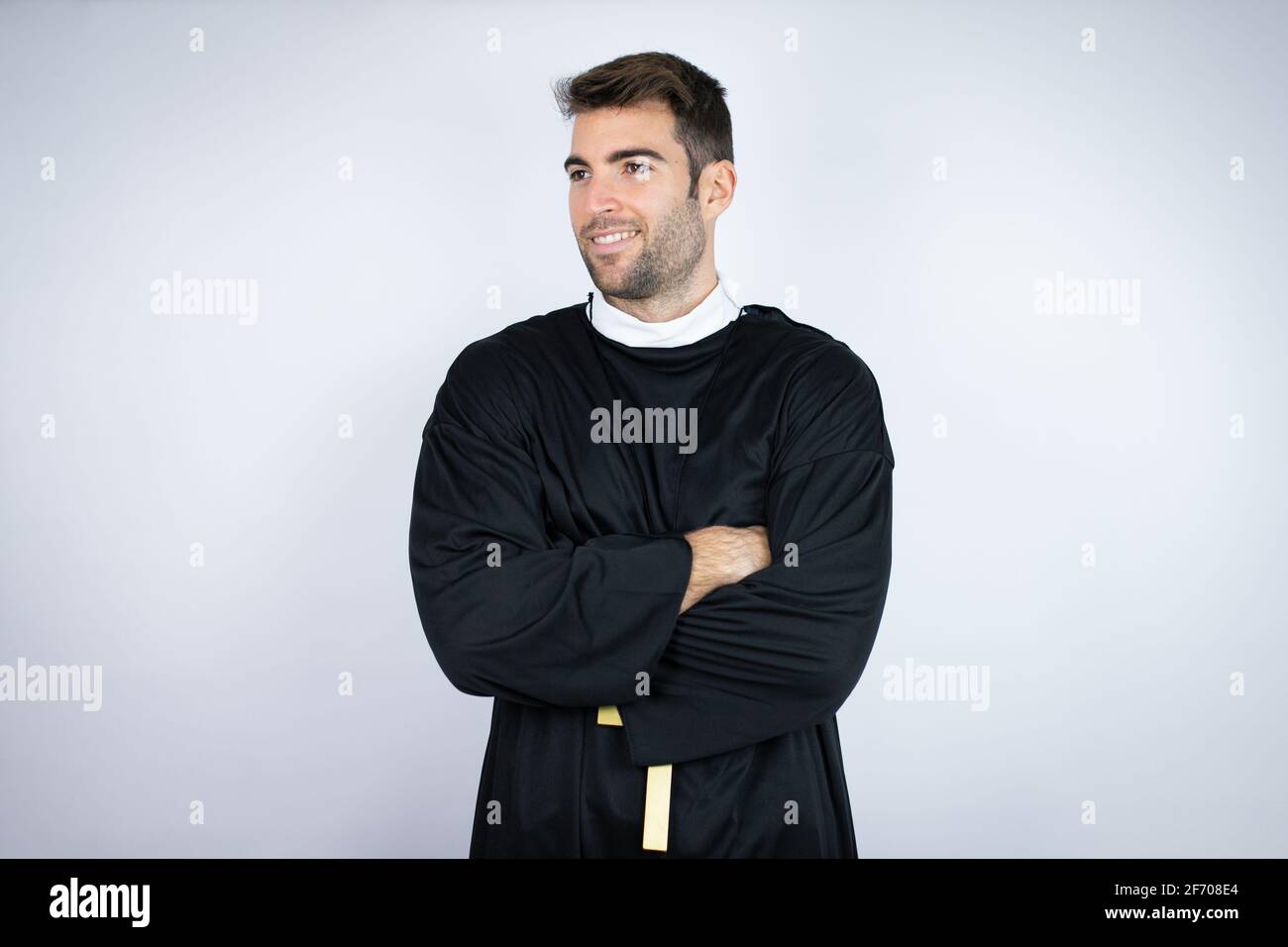 Young hispanic man wearing priest uniform standing over white ...