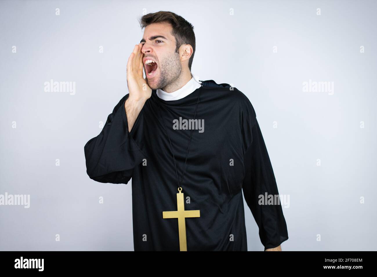 Young hispanic man wearing priest uniform standing over white ...