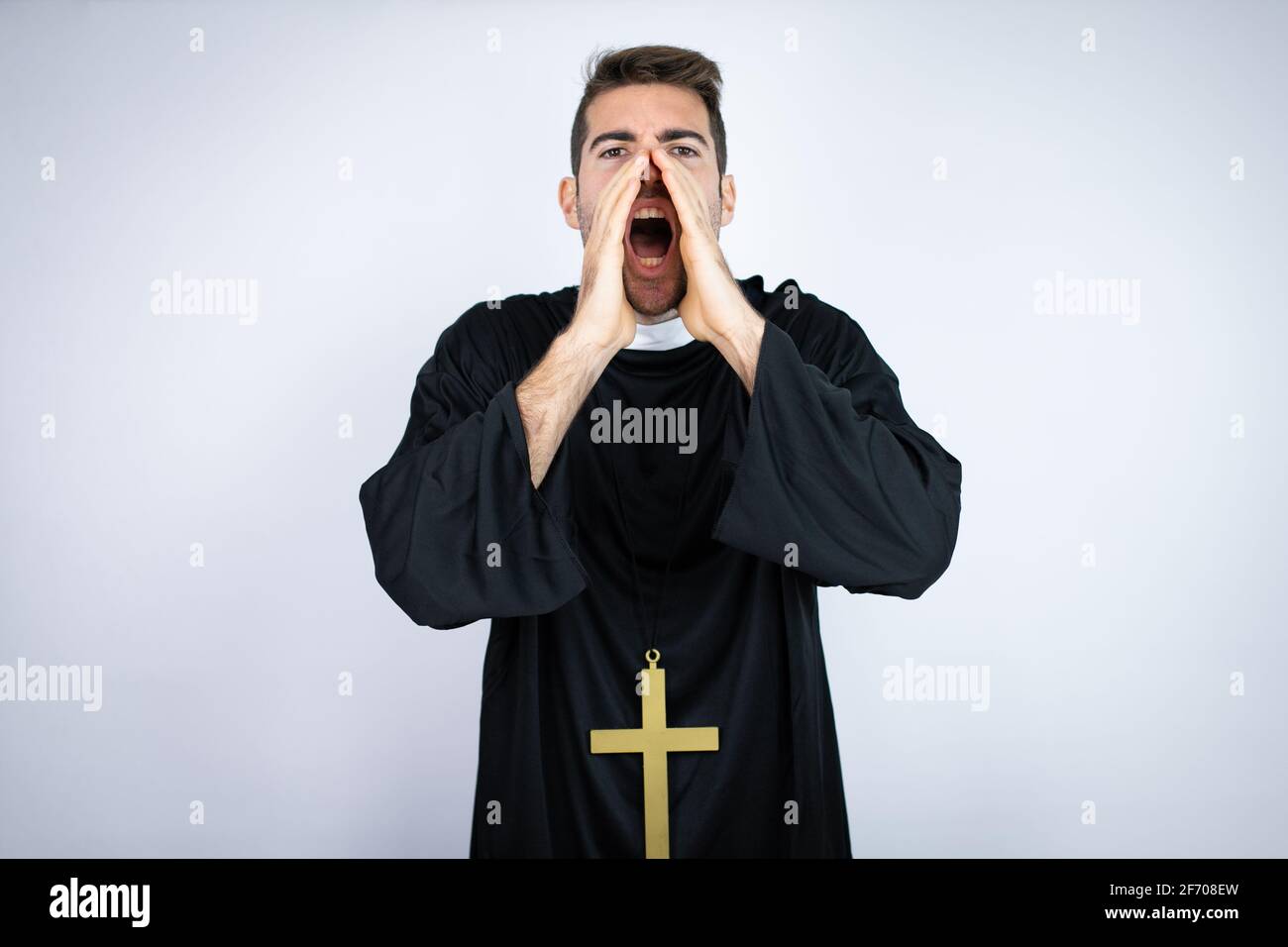 Young hispanic man wearing priest uniform standing over white ...