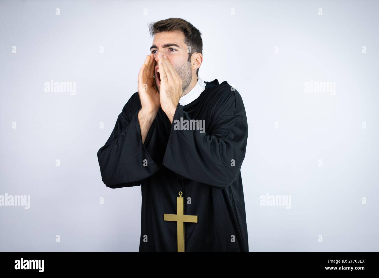 Young hispanic man wearing priest uniform standing over white ...
