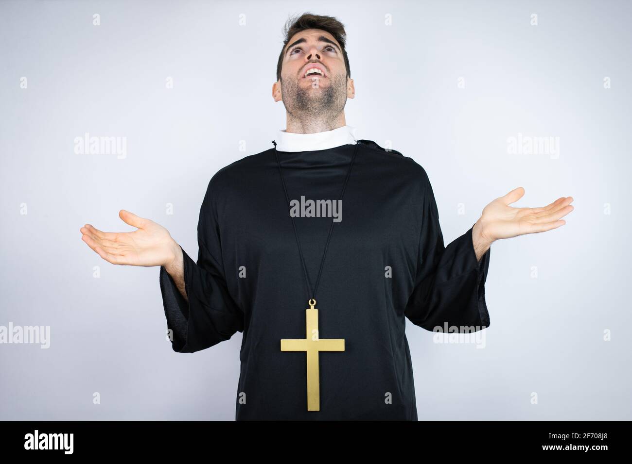 Young hispanic man wearing priest uniform standing over white ...