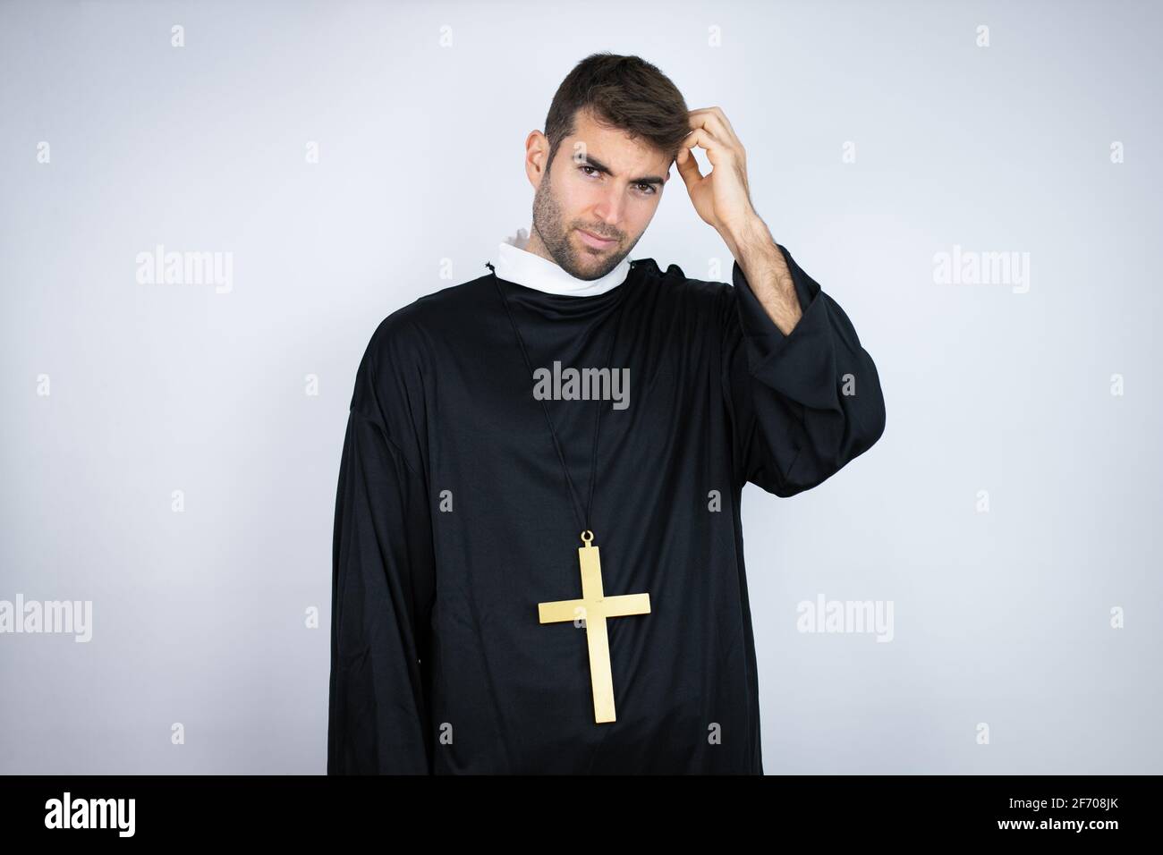 Young hispanic man wearing priest uniform standing over white ...