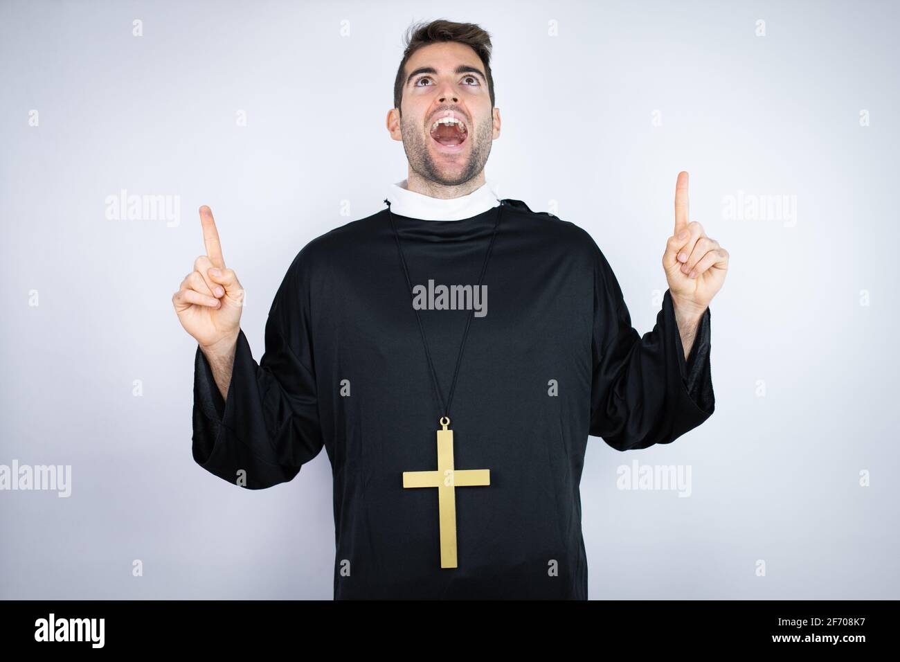 Young hispanic man wearing priest uniform standing over white ...
