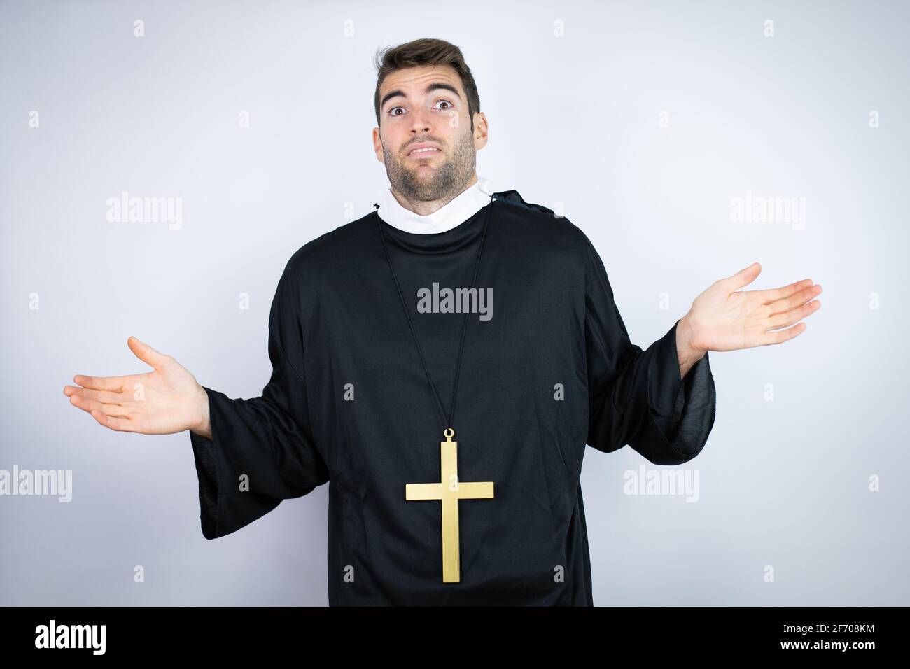 Young hispanic man wearing priest uniform standing over white ...