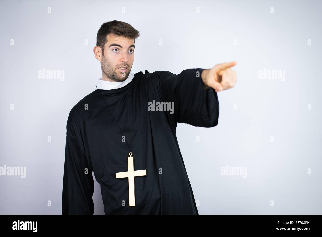 Young hispanic man wearing priest uniform standing over white ...