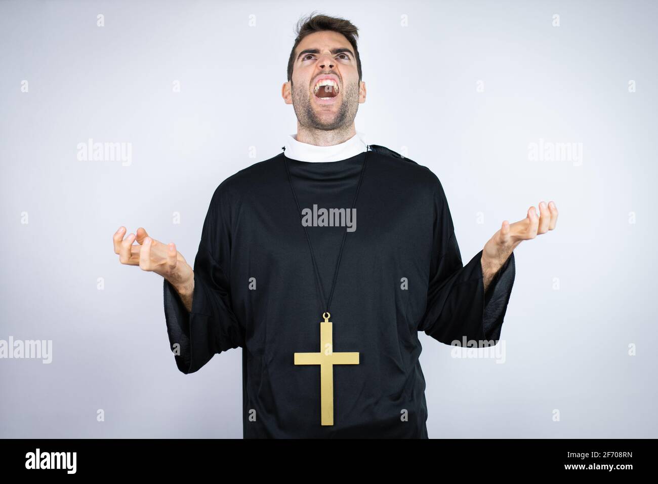Young hispanic man wearing priest uniform standing over white ...