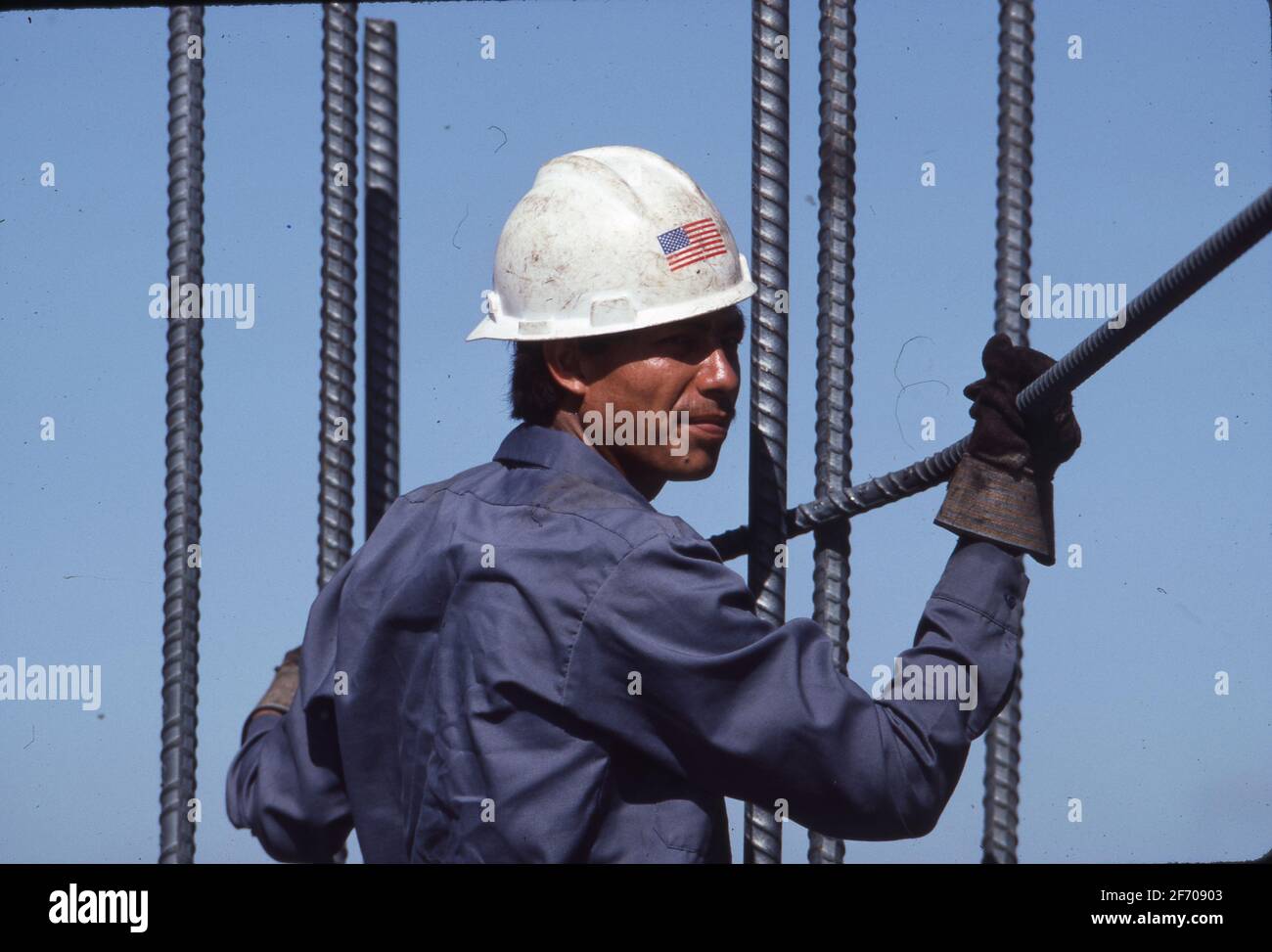 Hispanic construction worker wears a hard hat for safety at a high-rise ...