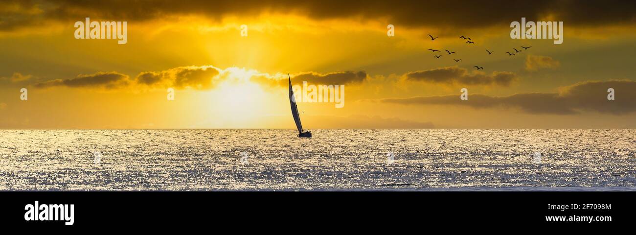 Sailboat sailing towards the sunset sun in the Mediterranean sea Stock ...